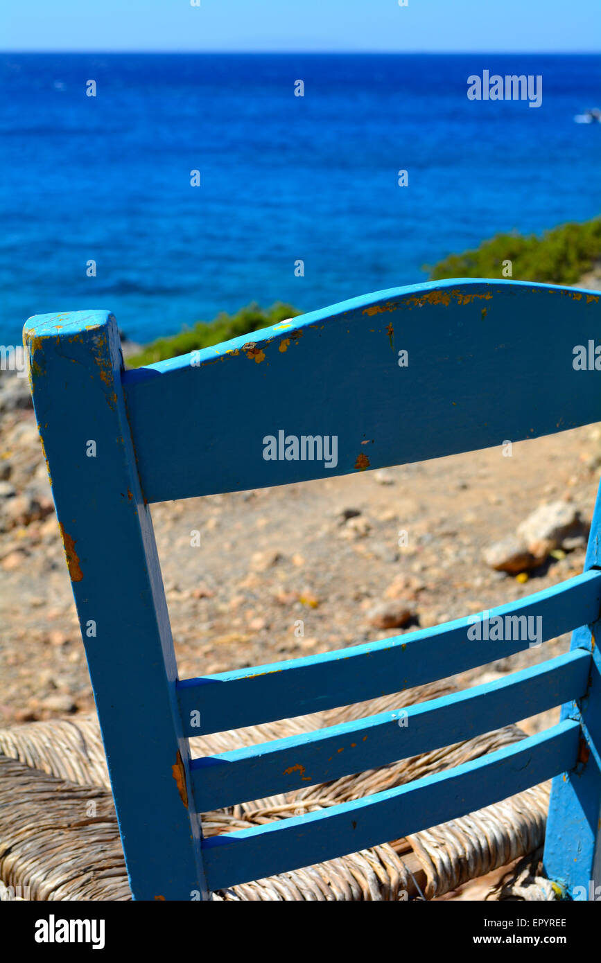 A wooden blue chair facing the sea on the island of Crete Greece Stock ...