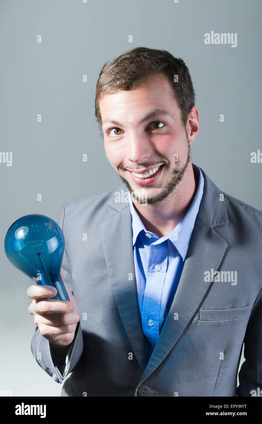Handsome young smart man holding a blue light bulb Stock Photo - Alamy