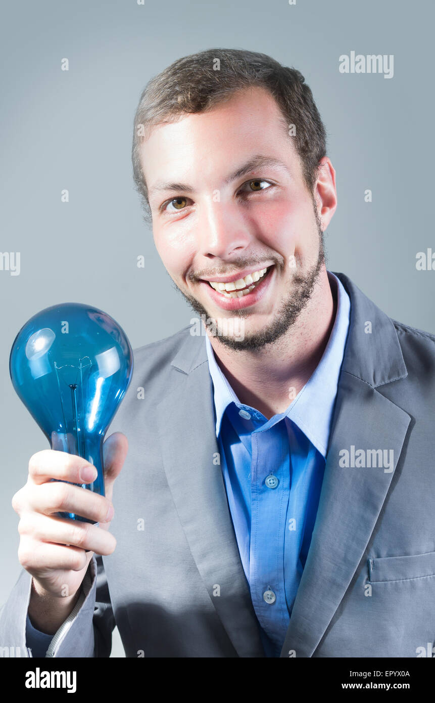 Handsome young smart man holding a blue light bulb Stock Photo - Alamy