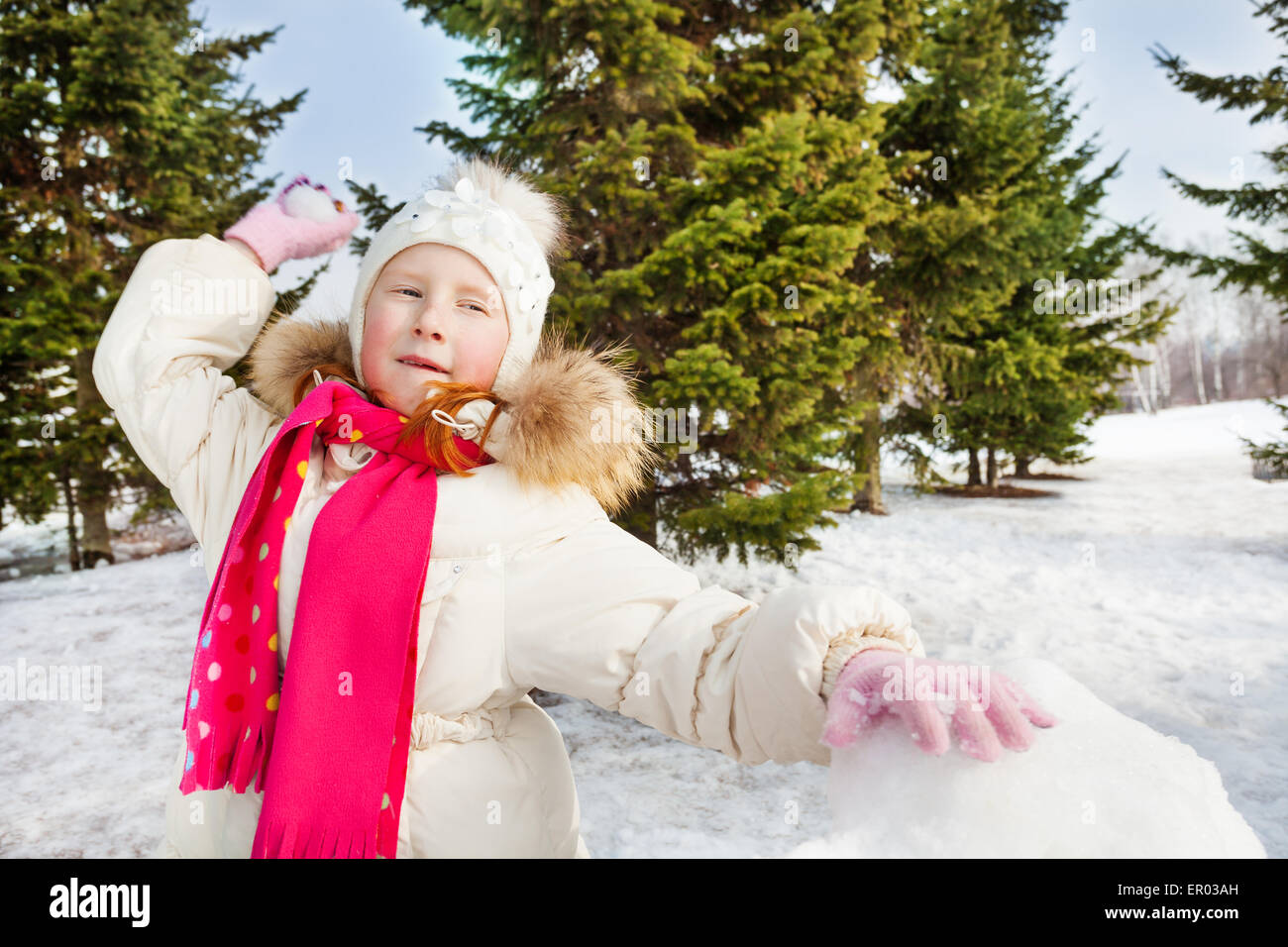 Cute girl ready to throw snowball during day Stock Photo - Alamy