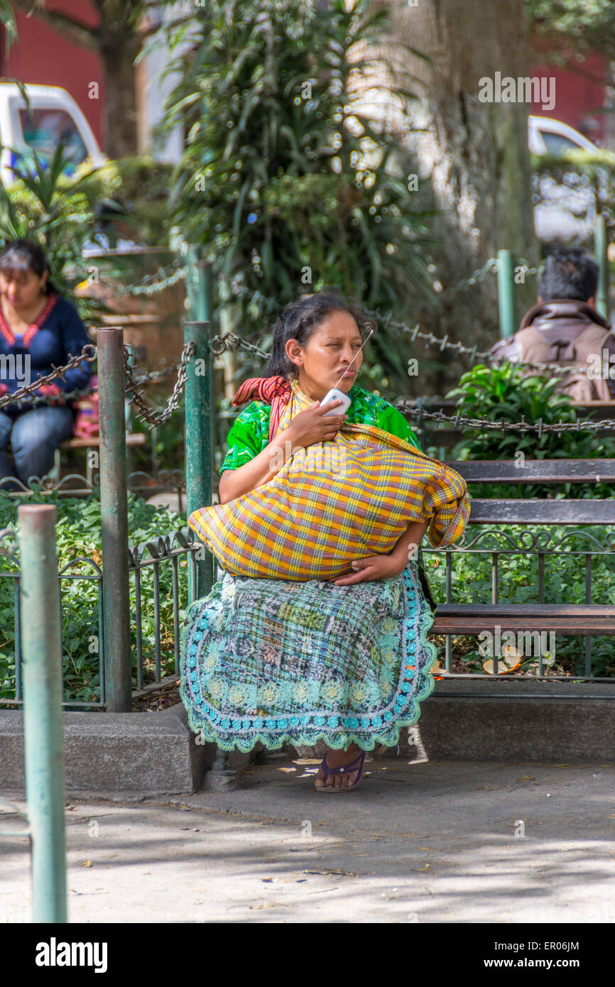 Guatemalan woman in traditional Mayan dress holding a cell phone and a ...