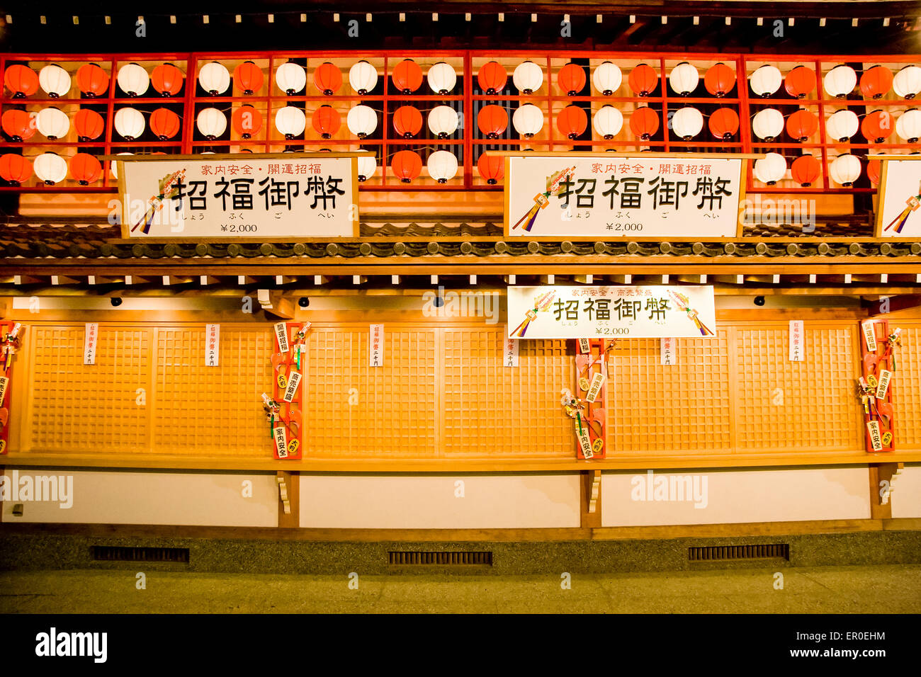 Closed omikuji counter selling points with three rows of red and white paper lanterns above, at ...