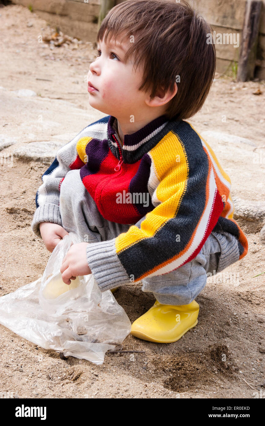 Young child, boy, 3-4 year old, crouching down outdoors in park playing ...