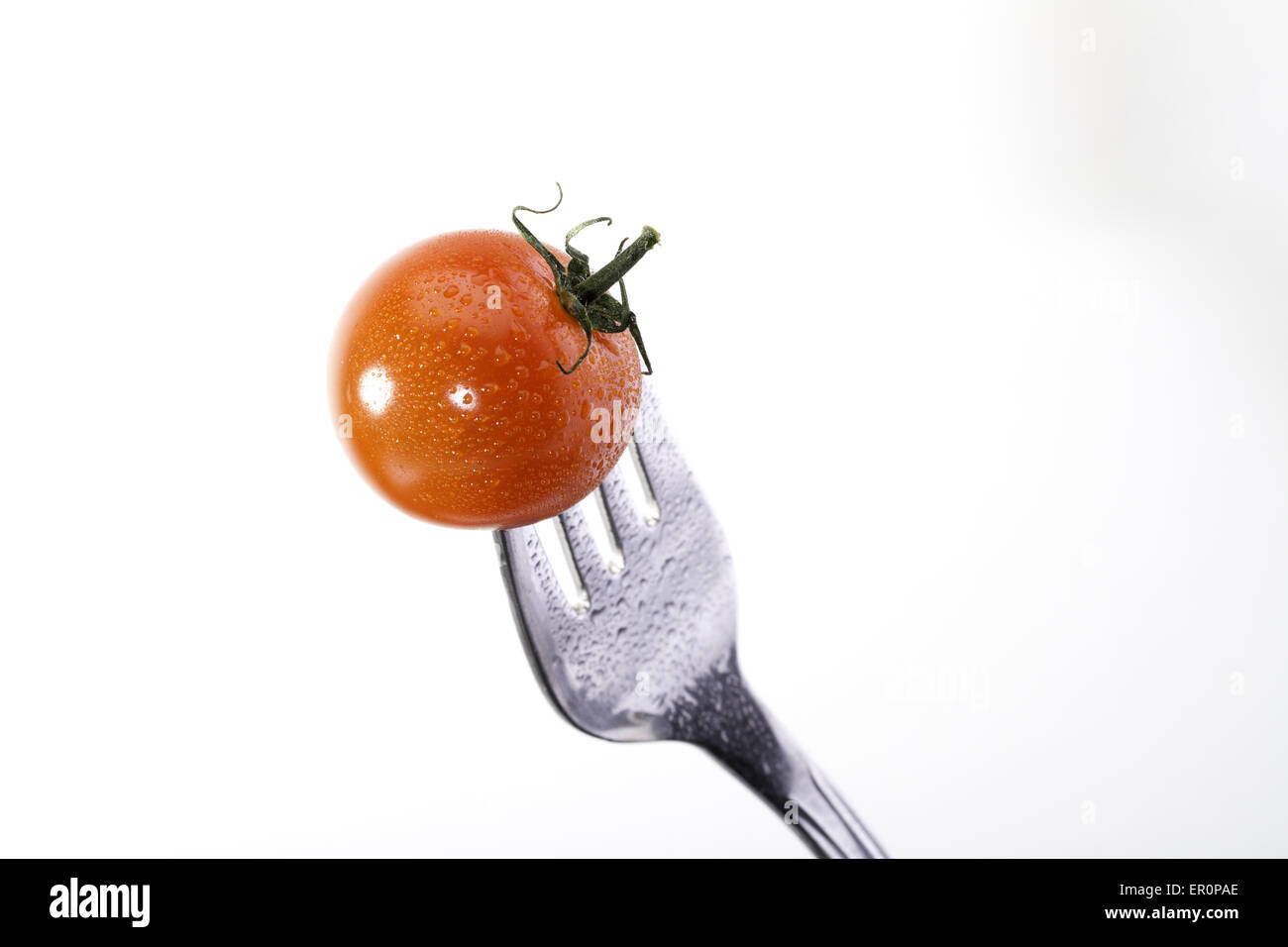 Fresh sherry tomato with fork on a white background Stock Photo - Alamy