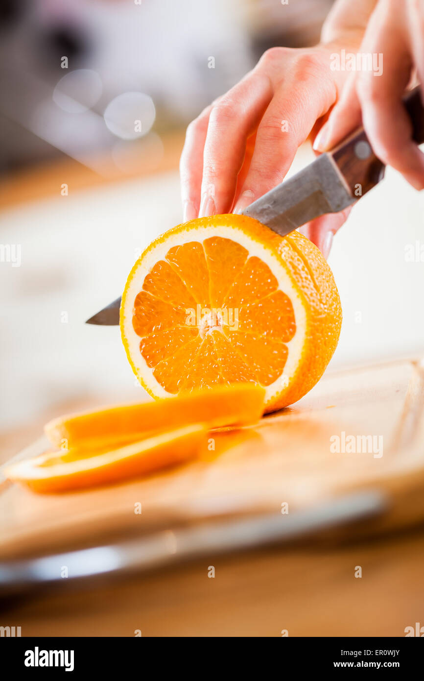 Woman's hands cutting fresh orange on kitchen Stock Photo - Alamy