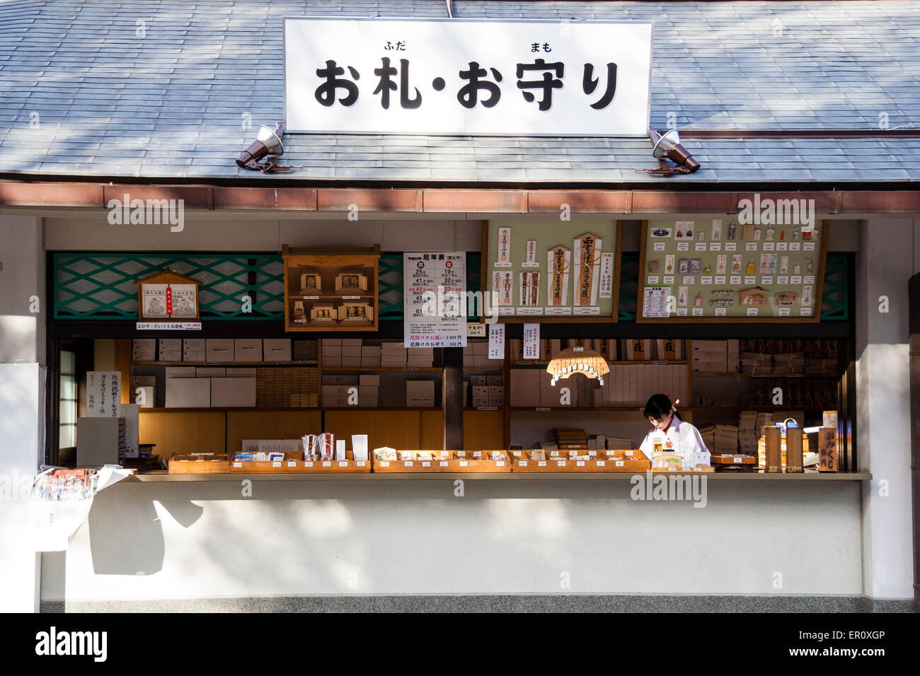 Lone Japanese Shinto shrine maiden, Miko, sitting at one end of large ...