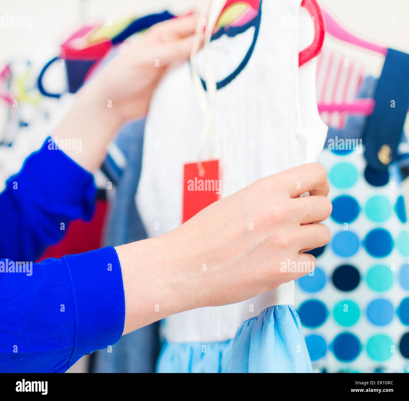 Woman's hand choosing child dress at clothing store Stock Photo - Alamy