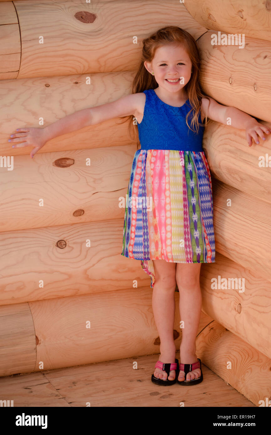 Pretty 4 year old girl in colorful blue dress on log cabin Stock Photo ...