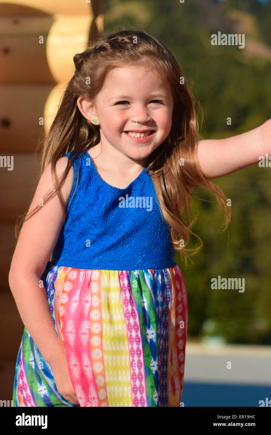 Pretty 4 year old girl in colorful blue dress on log cabin Stock Photo ...