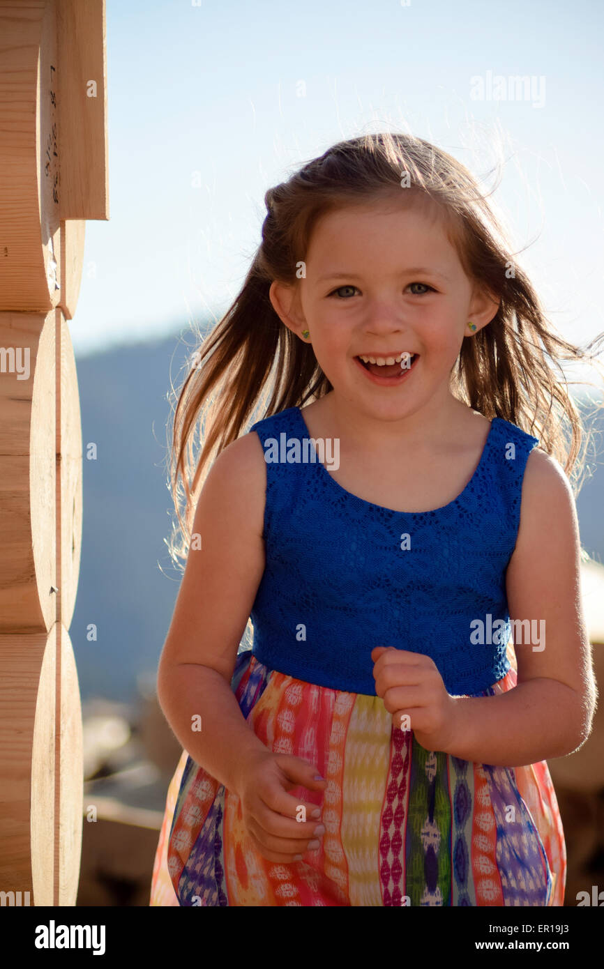 Pretty 4 year old girl in colorful blue dress on log cabin Stock Photo ...