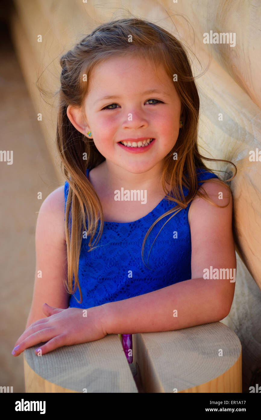 Pretty 4 year old girl in colorful blue dress on log cabin Stock Photo ...