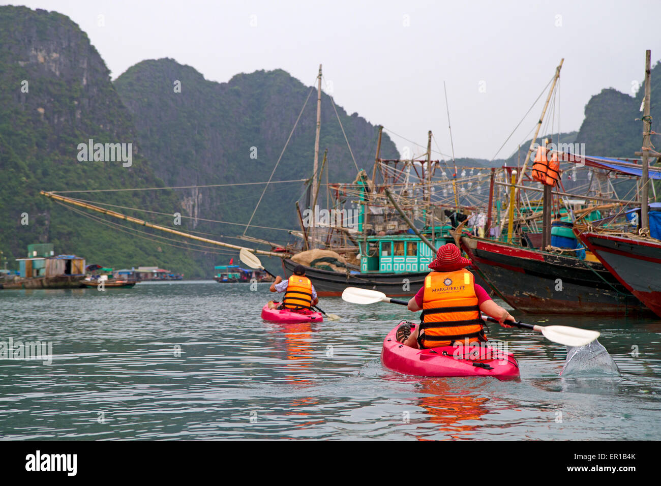 Kayaking past fishing boat in Cua Van, the largest floating village in ...