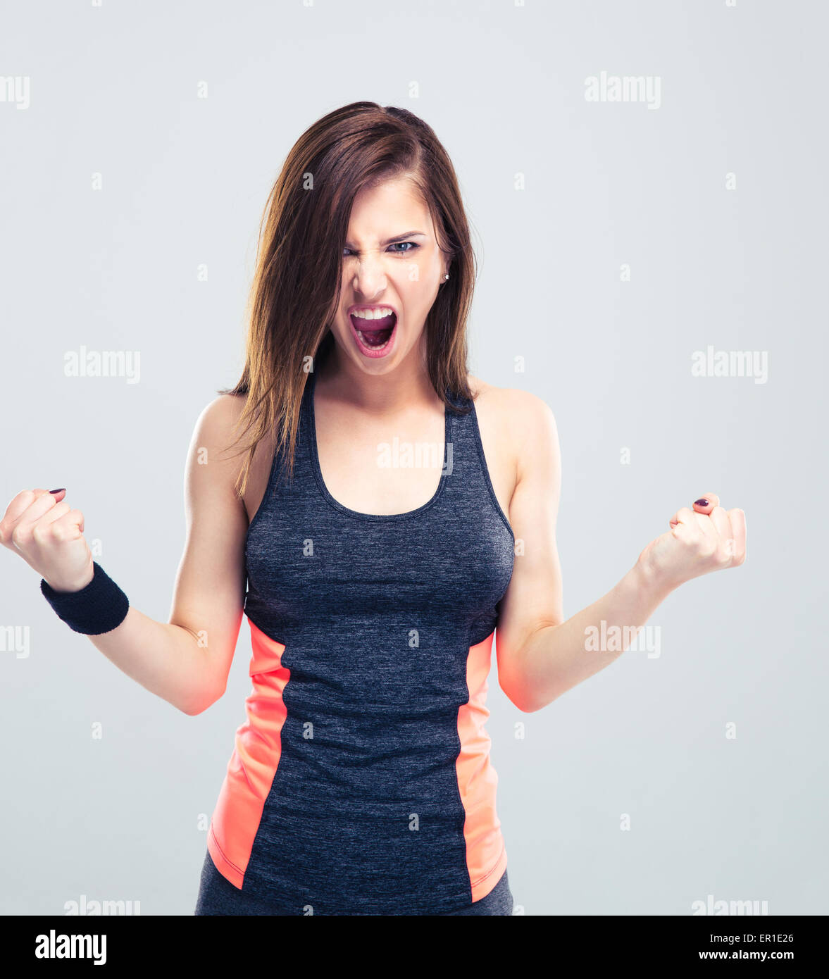 Angry young fitness woman screaming on gray background and looking at ...