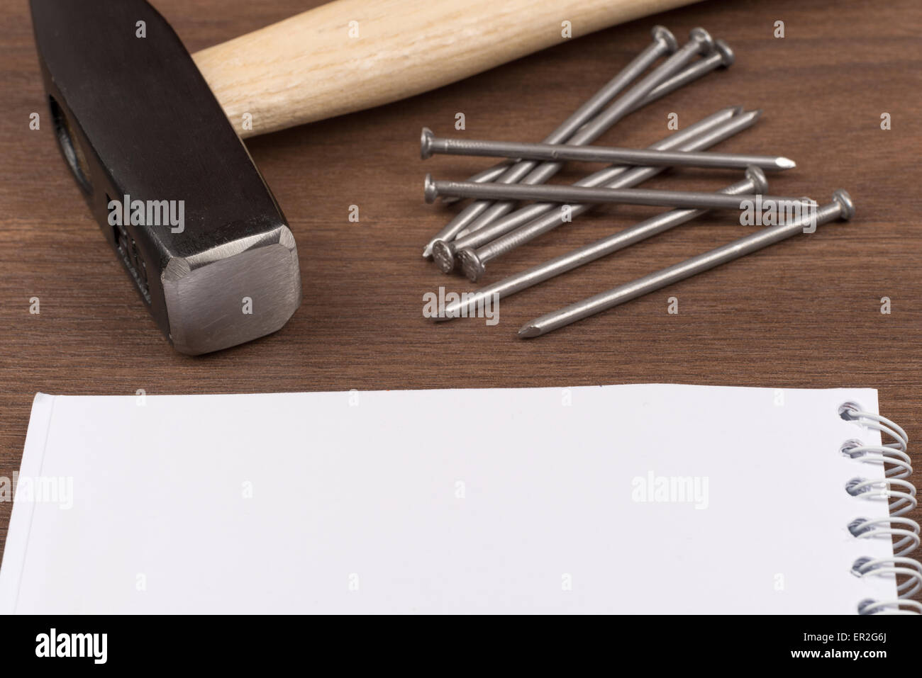 Hammer with note pad and nails on table Stock Photo - Alamy