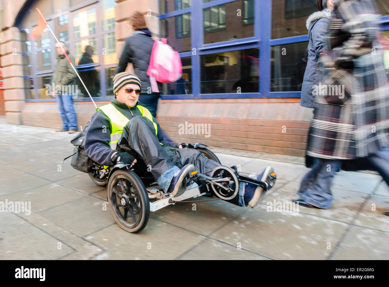 A man rides a recumbent bicycle along a busy footpath narrowly avoiding ...