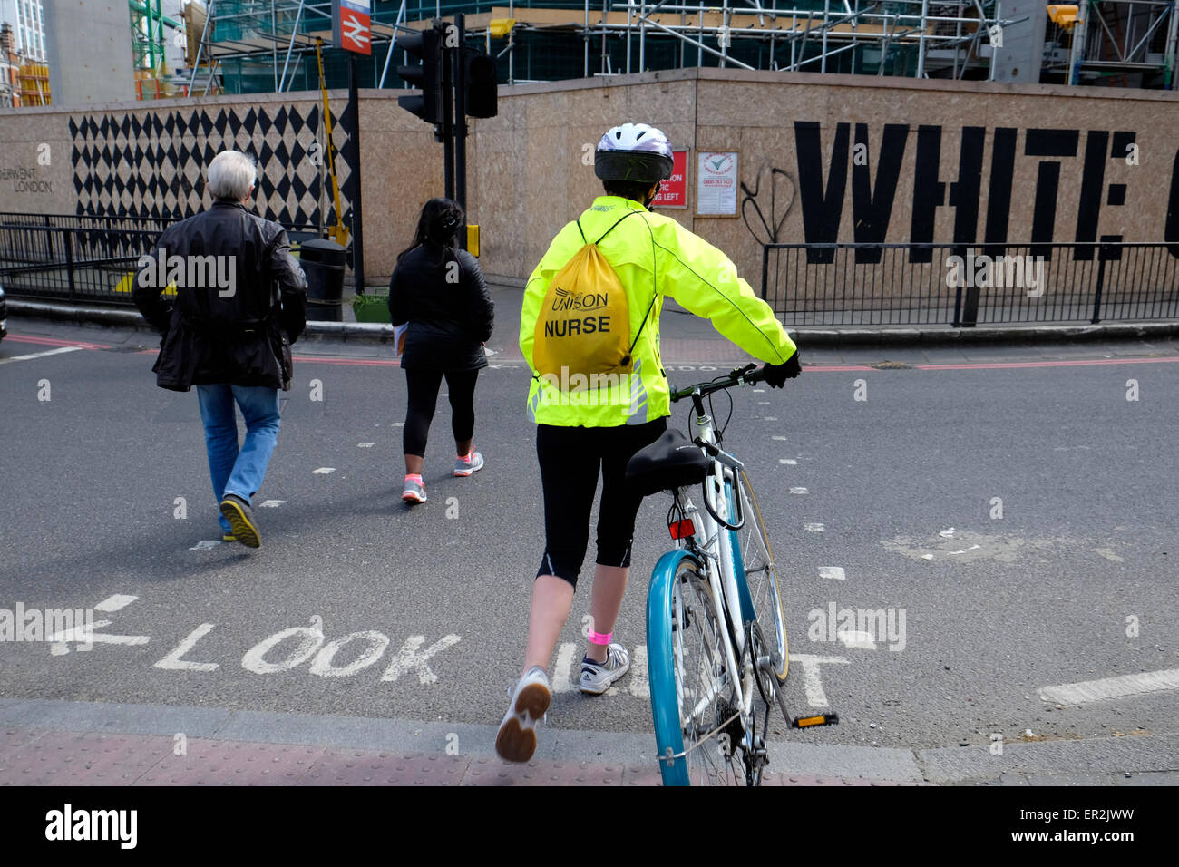 Rear back view of woman female cyclist with bicycle bike walking on a ...