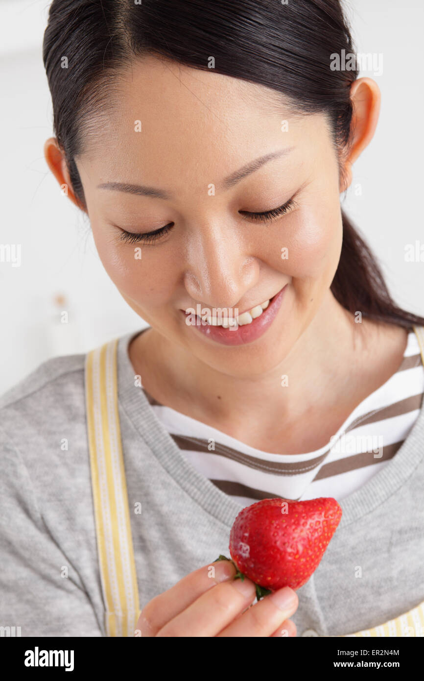 Woman eating strawberry in an open kitchen Stock Photo - Alamy