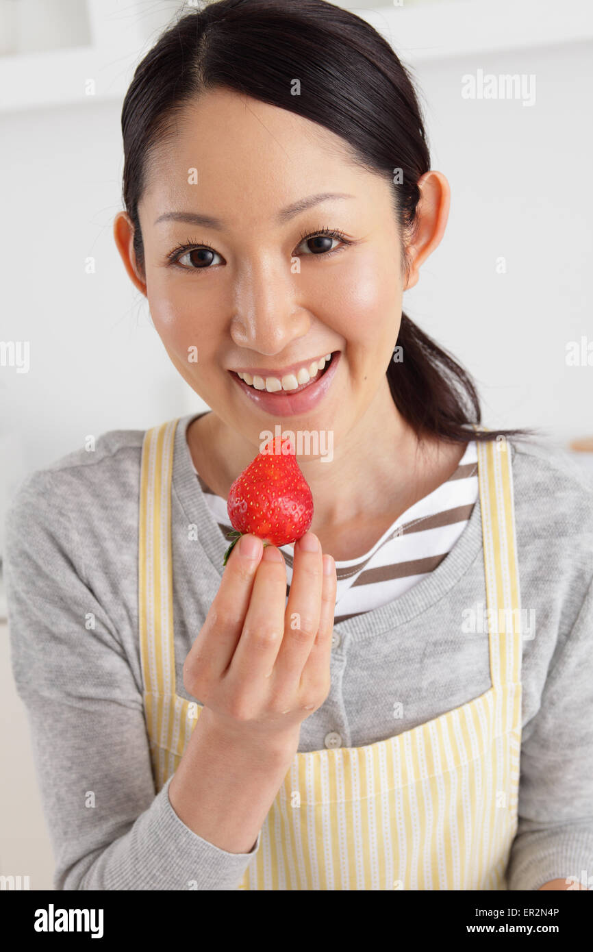 Woman eating strawberry in an open kitchen Stock Photo - Alamy