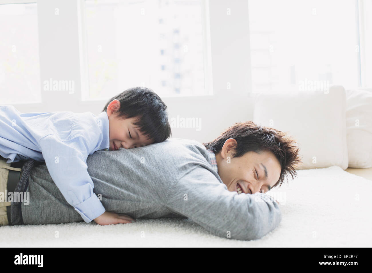 Young boy laying on his fathers back Stock Photo - Alamy