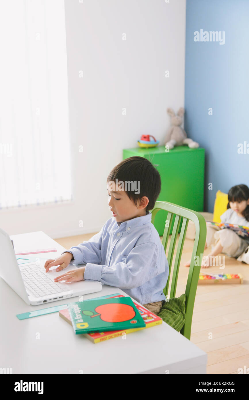 Elementary age boy doing his homework at his desk with his sister ...
