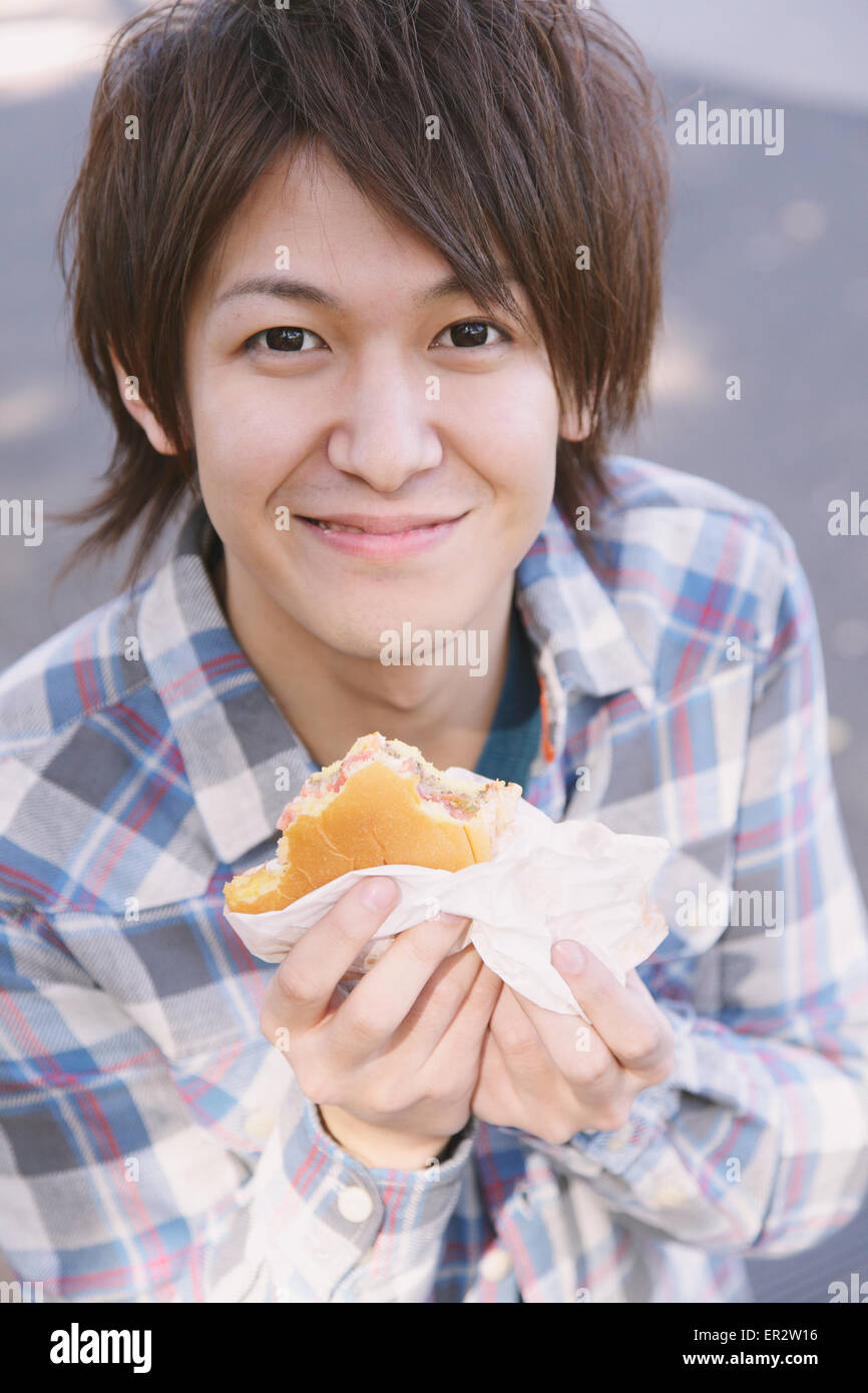Young man eating a sandwich Stock Photo - Alamy