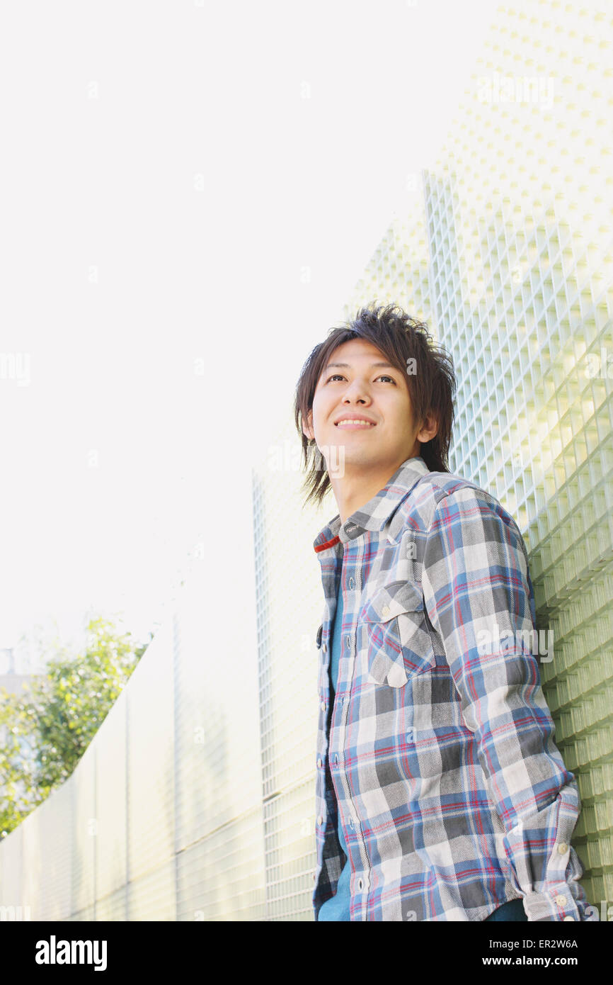 Young man leaning against a wall Stock Photo - Alamy