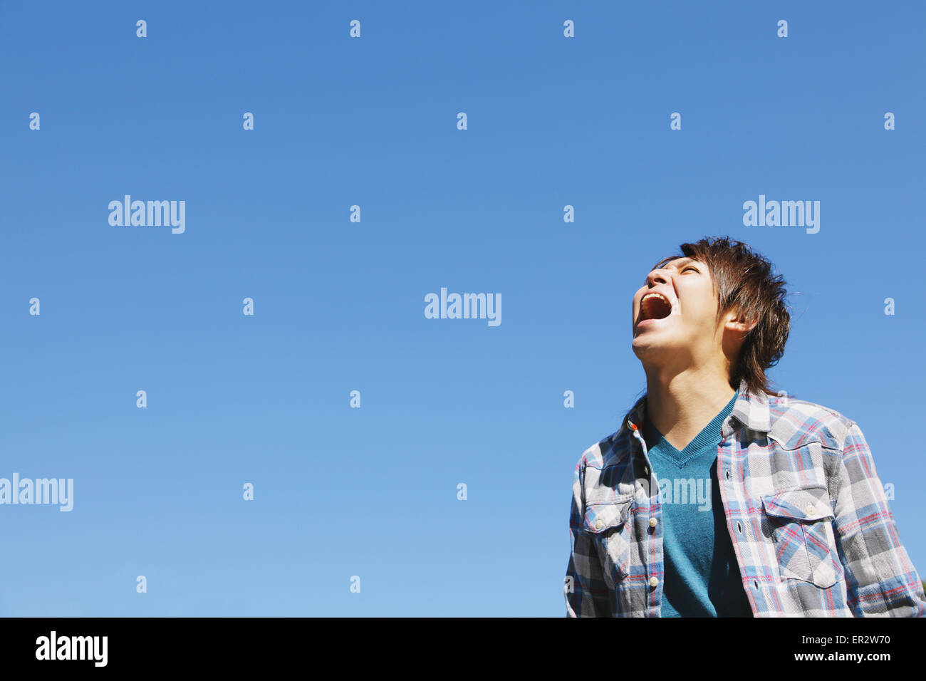 Young man shouting against blue sky Stock Photo - Alamy