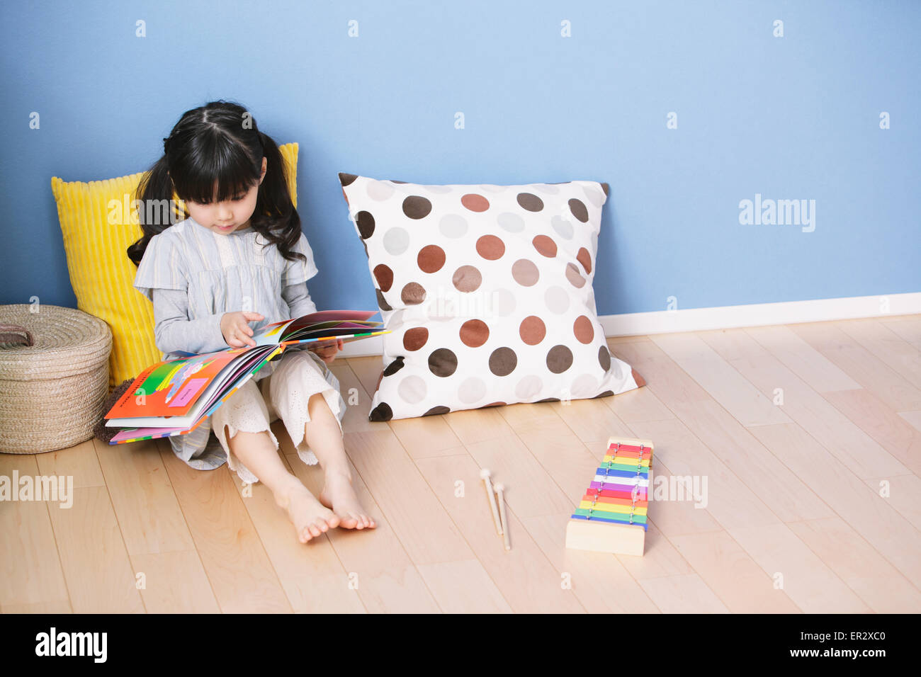 Elementary age girl reading an illustrated book on the floor of the ...