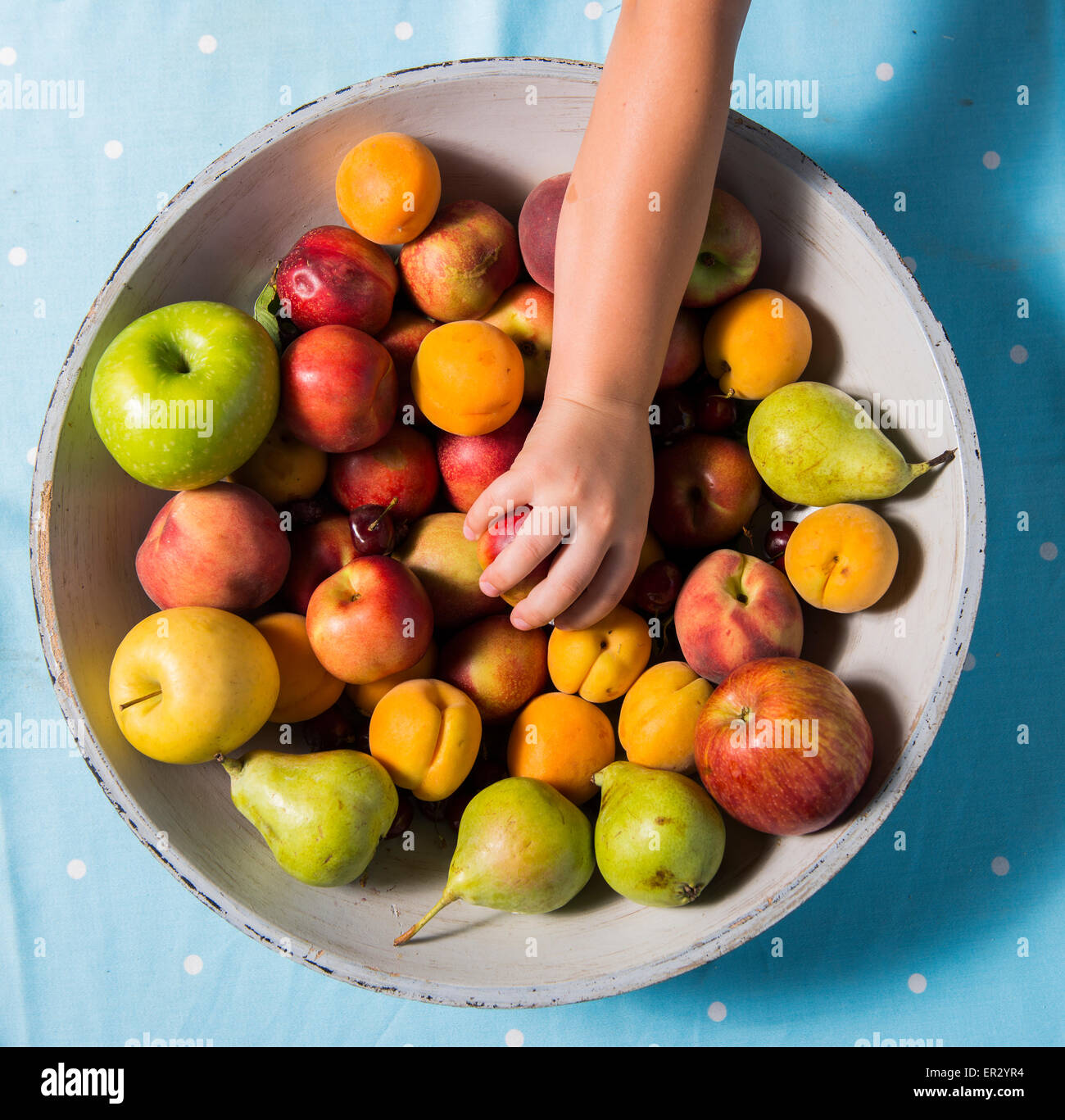 hand reaching for a fruit in a bowl, blue background Stock Photo - Alamy
