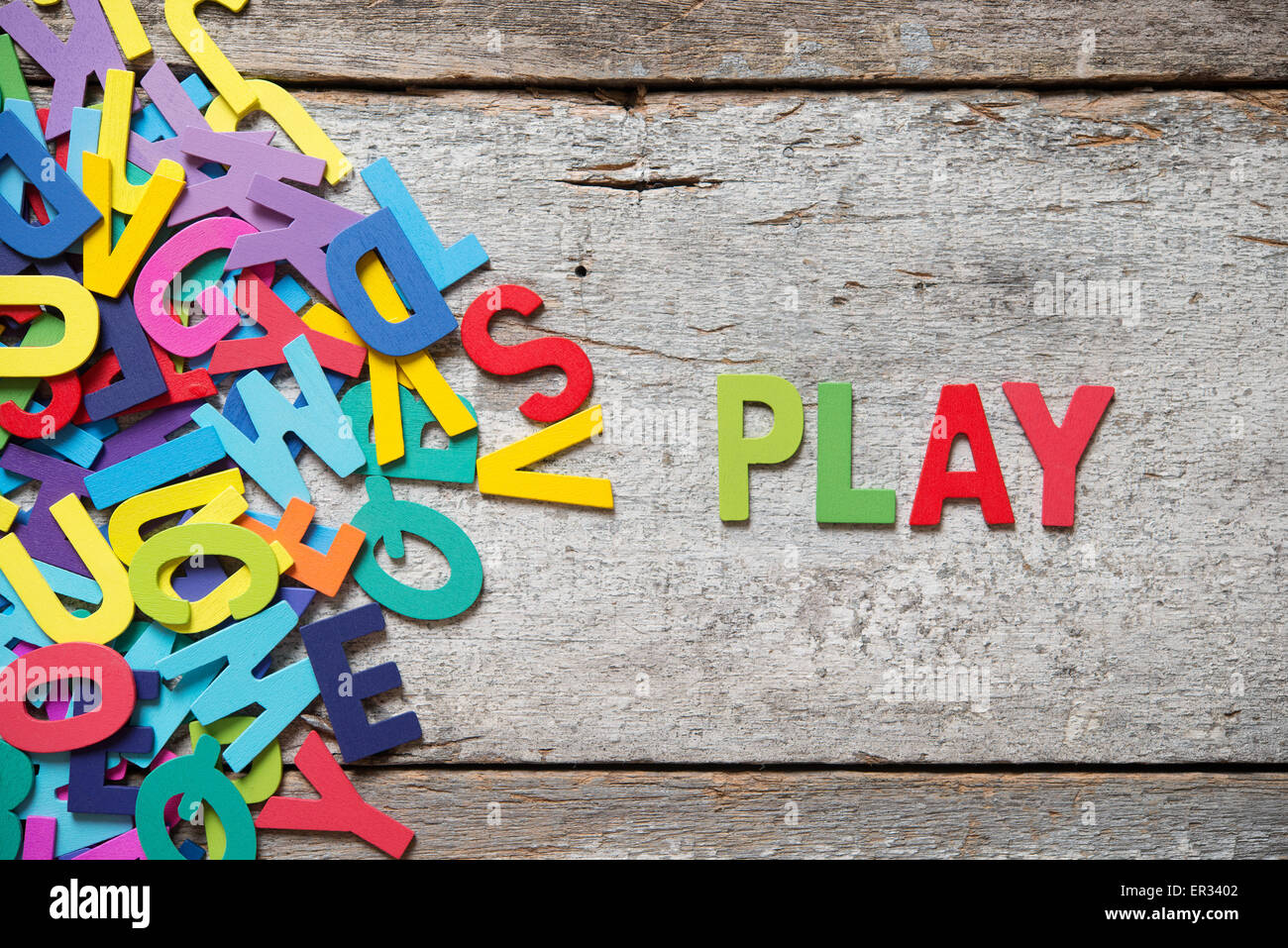 The colorful words "PLAY" made with wooden letters next to a pile of ...