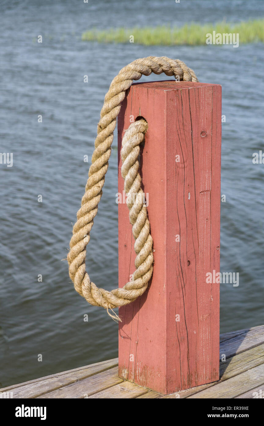 Red wooden boat bollard and rope on edge wooden dock Stock Photo - Alamy