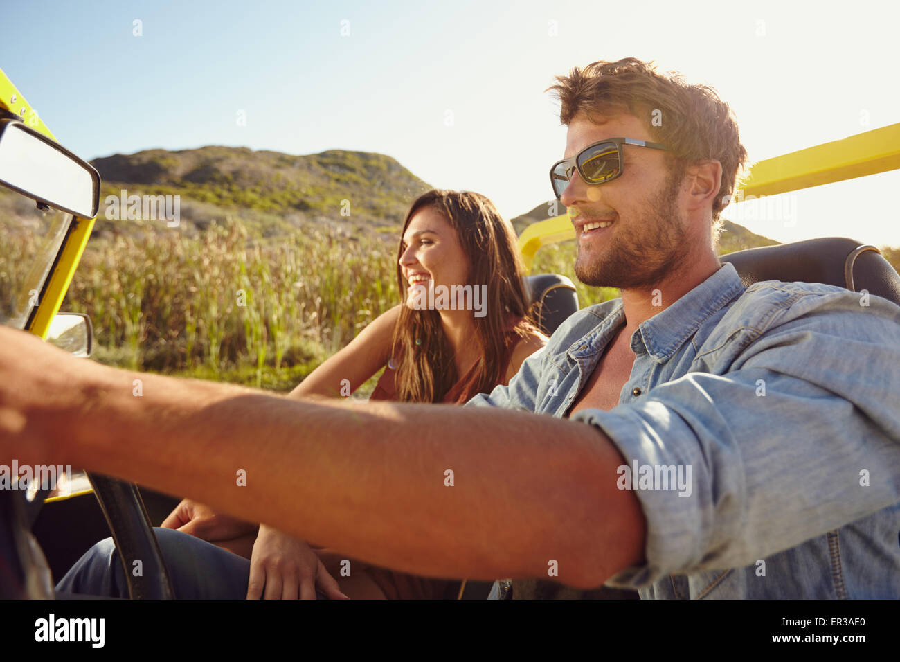 Young friends out for a drive together in a open topped car. Couple on ...