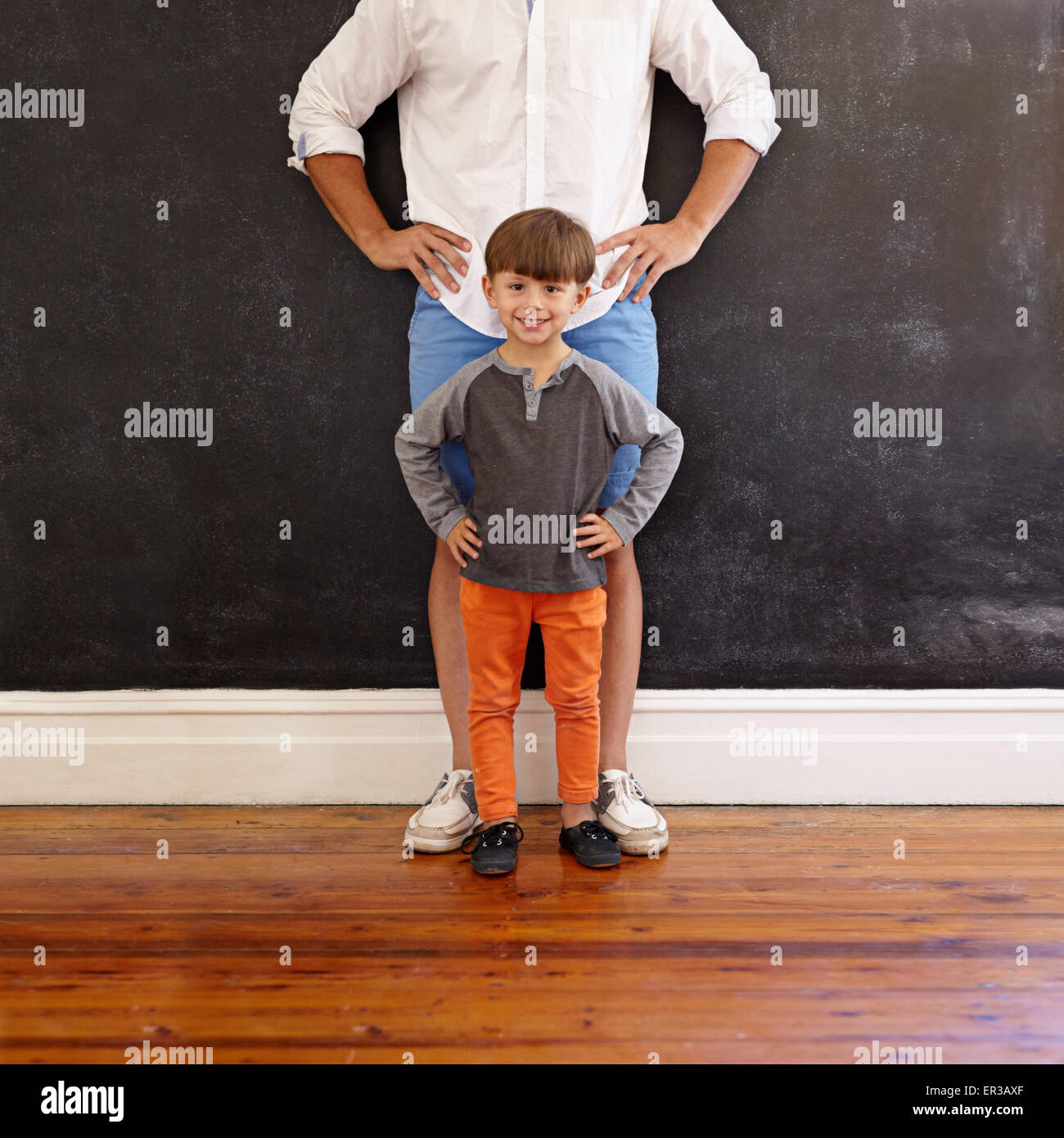 Indoor shot of little boy and his father standing with their hands on ...