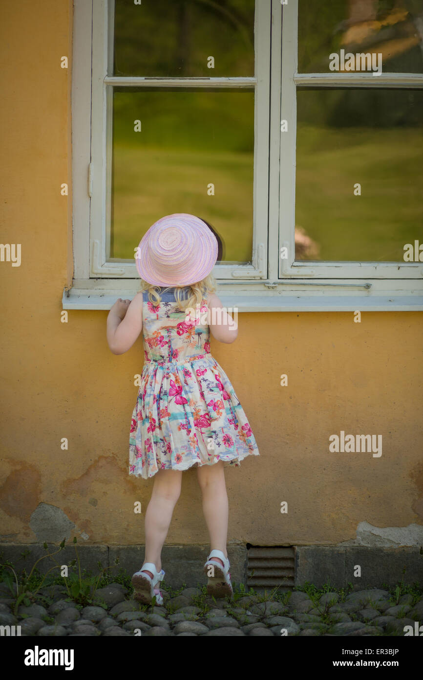 Rear view of a girl looking through a window Stock Photo - Alamy