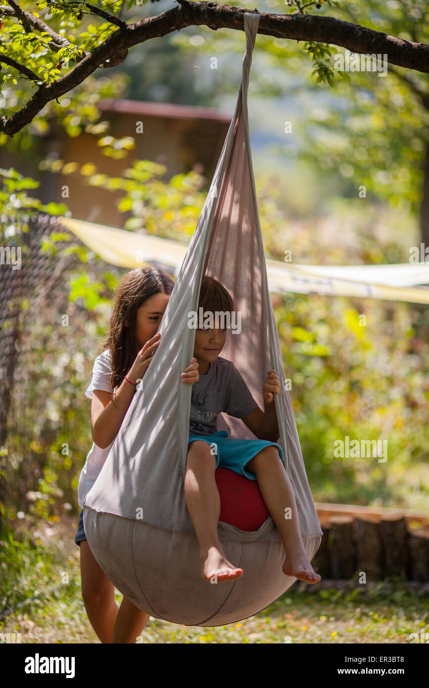 Boy pushing a girl sitting on a swing hi-res stock photography and ...