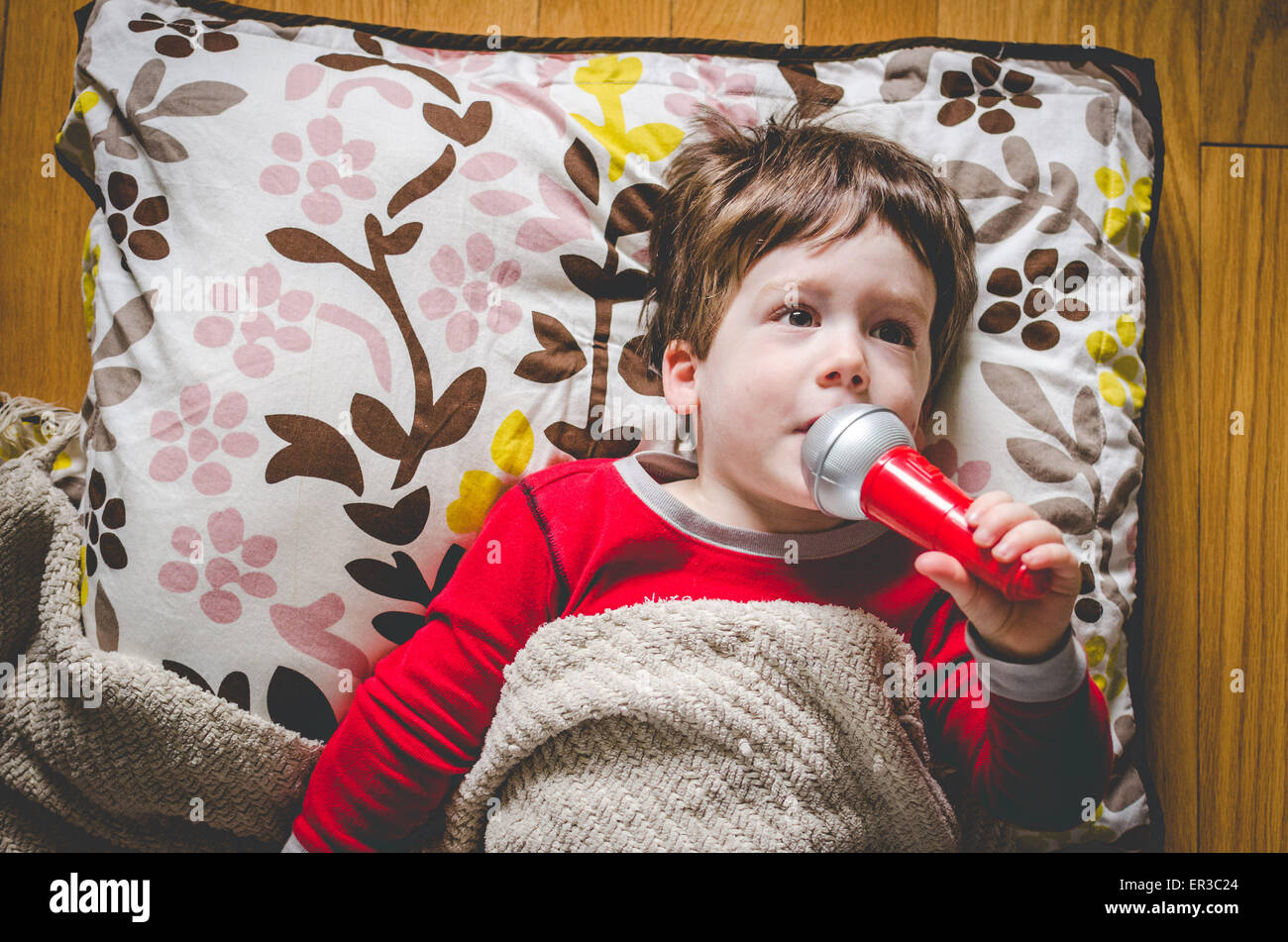 Little boy lying on the floor singing into a toy microphone Stock Photo ...