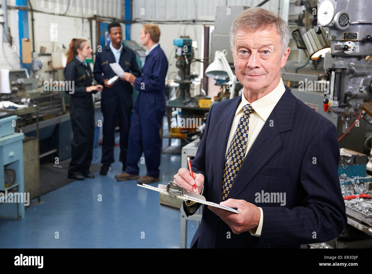 Owner Of Engineering Factory With Staff In Background Stock Photo - Alamy