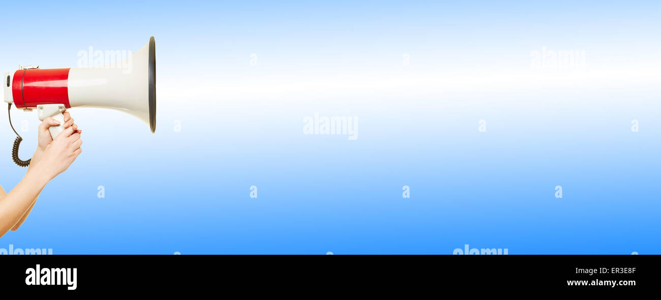 Female hand holding a big megaphone in front of a blue background Stock ...