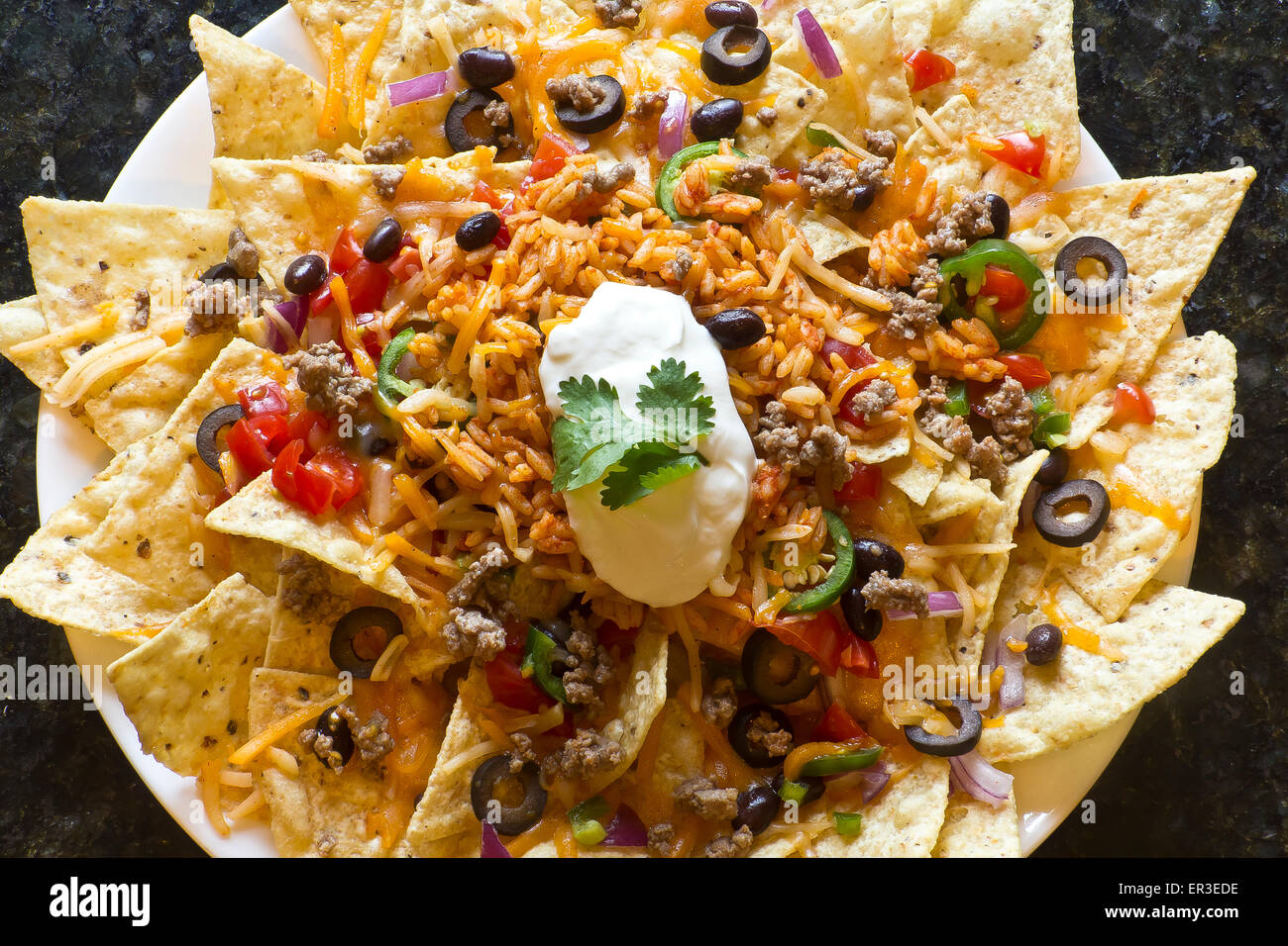 Mexican nachos with sour cream, black olives, ground beef, black beans ...
