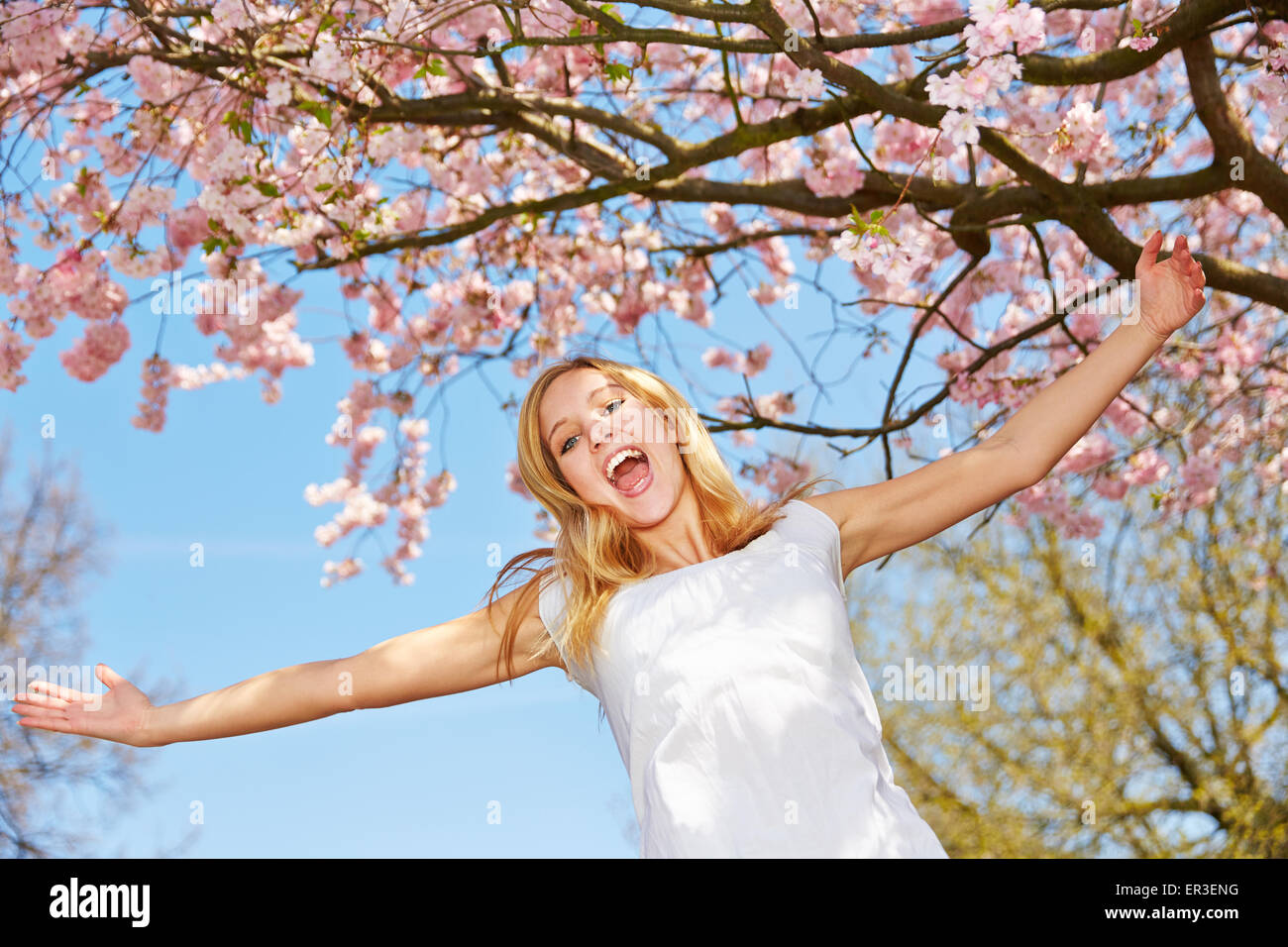 Cheering happy girl under pink cherry blossom tree in a garden Stock ...