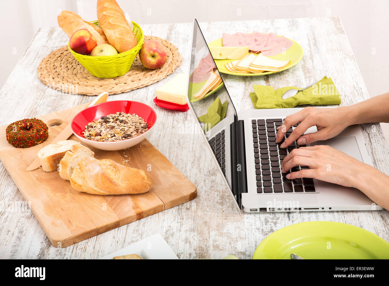 A young woman having breakfast while using a laptop computer Stock ...