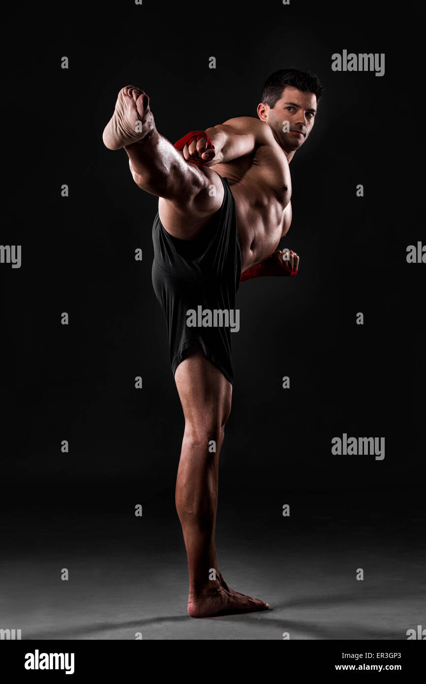 Portrait of a muscular man practicing body combat against a dark ...