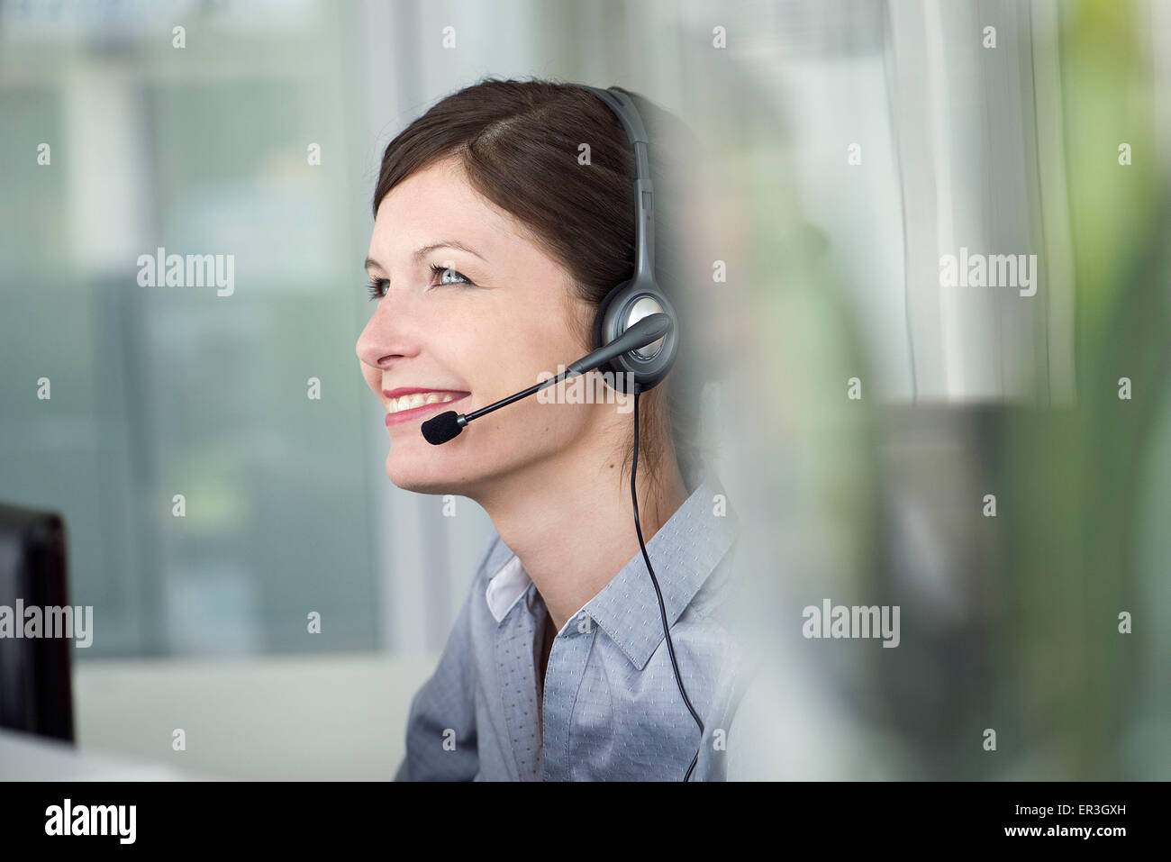 Receptionist wearing headset, smiling cheerfully Stock Photo - Alamy