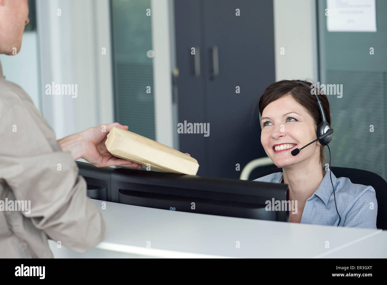 Receptionist receiving package from delivery person Stock Photo - Alamy