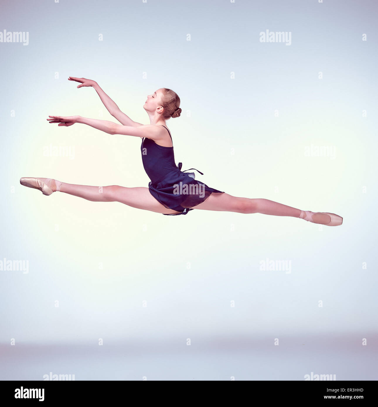 Beautiful young ballet dancer jumping on a gray background Stock Photo ...