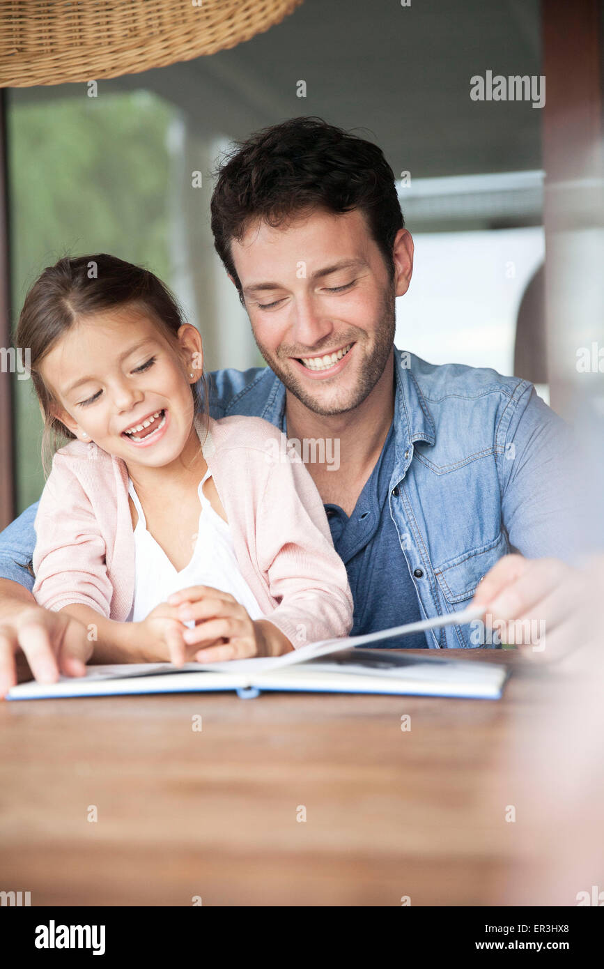 Father and daughter reading book together Stock Photo - Alamy
