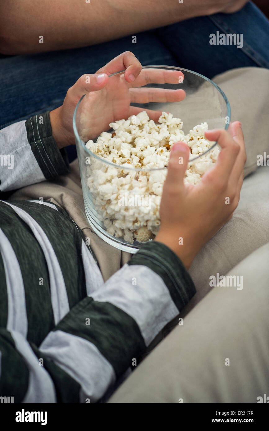 Child holding bowl of popcorn on lap, cropped Stock Photo - Alamy
