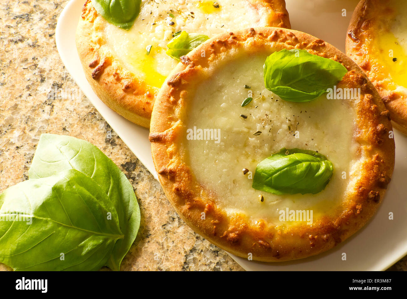 Pizzette, mini Italian pizzas served with fresh basil leaves Stock ...