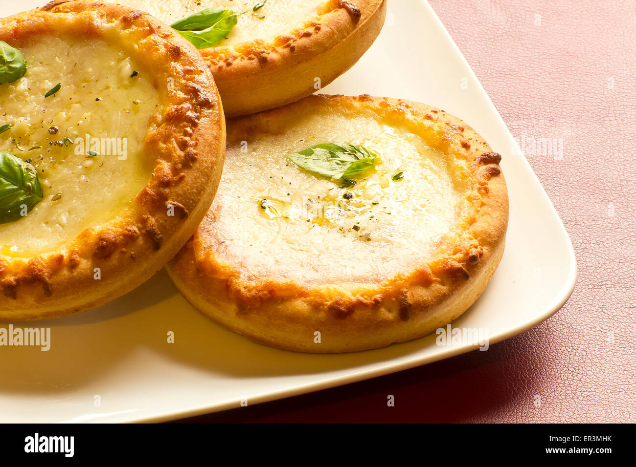 Pizzette, mini Italian pizzas served with fresh basil leaves Stock ...