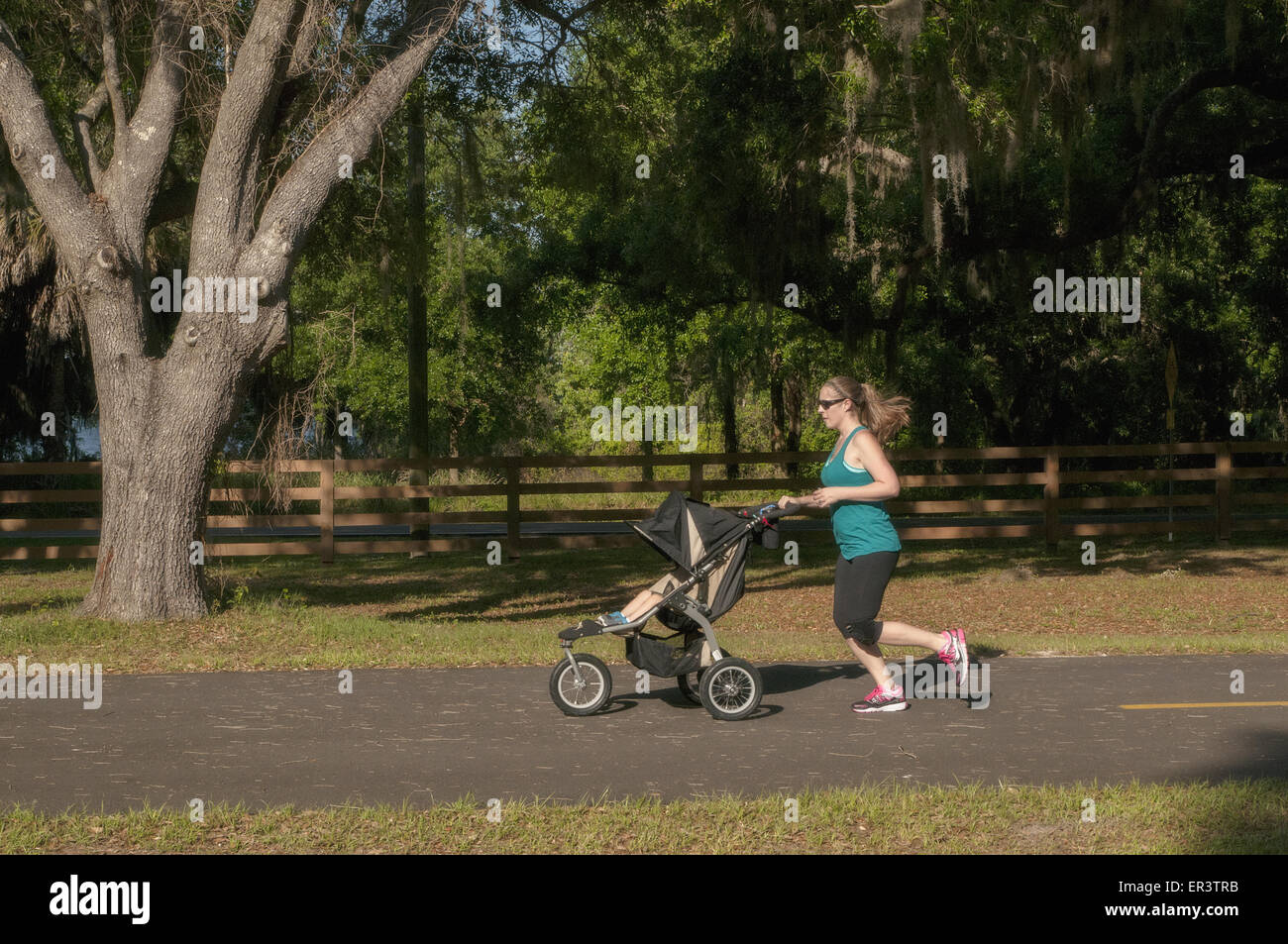 young woman jogging in a park while pushing a stroller Stock Photo - Alamy